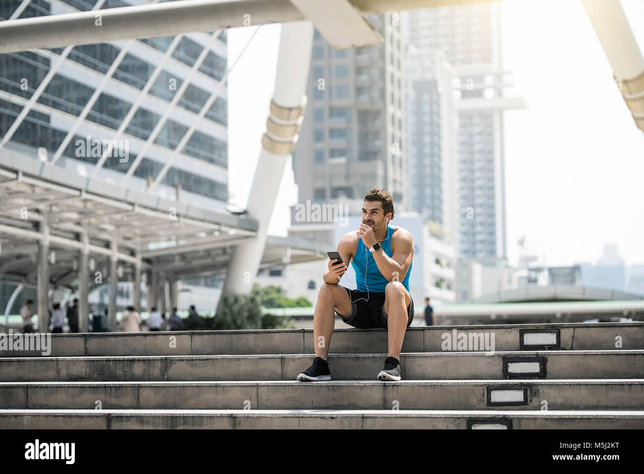 Runner wearing earphones, checking messages on his smartphone Stock ...