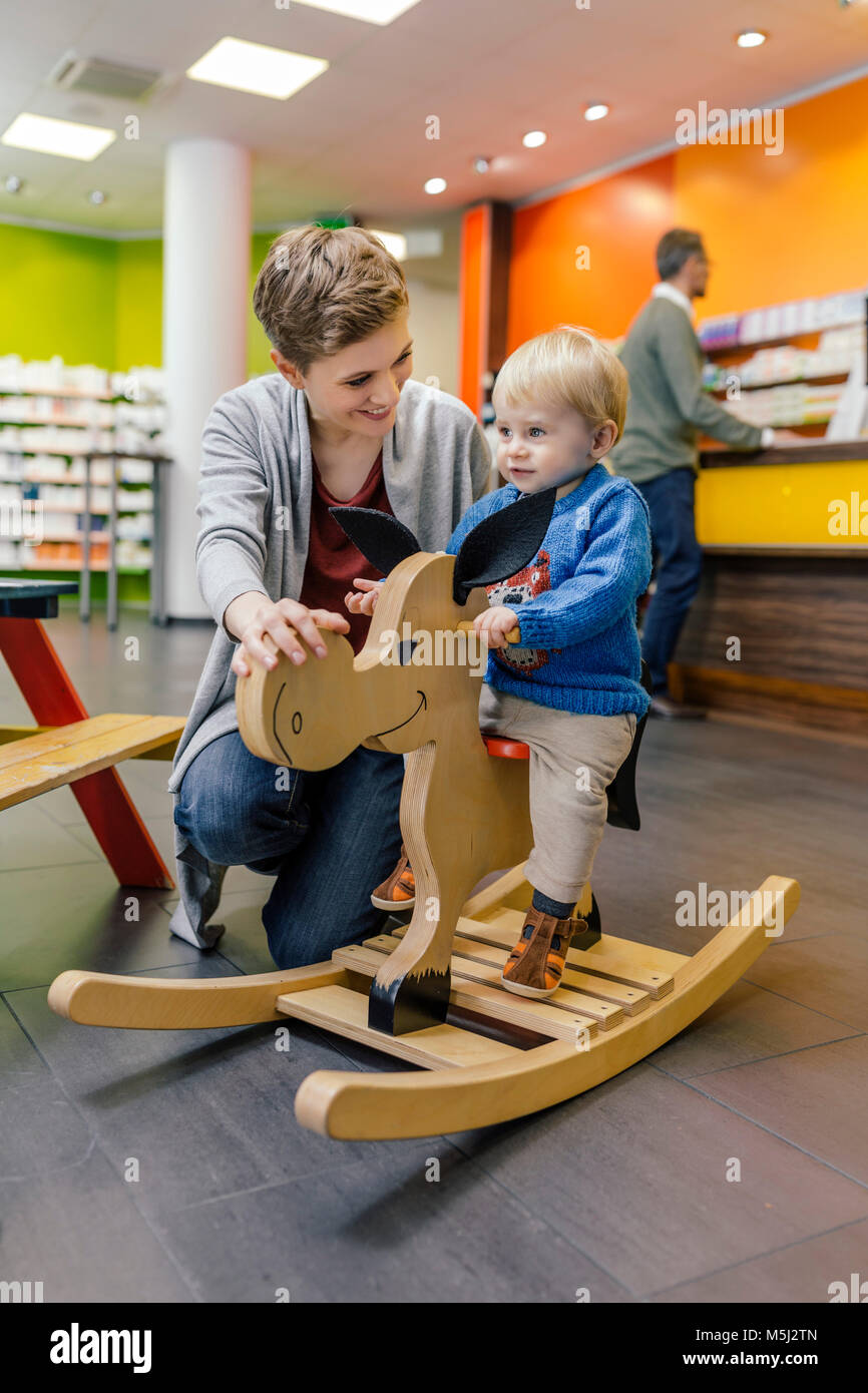 Little boy and mother playing with rocking horse in pharmacy Stock ...