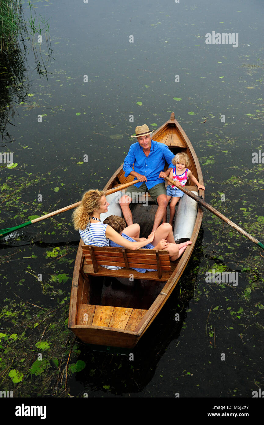 Family relaxing in rowing boat on lake Stock Photo - Alamy
