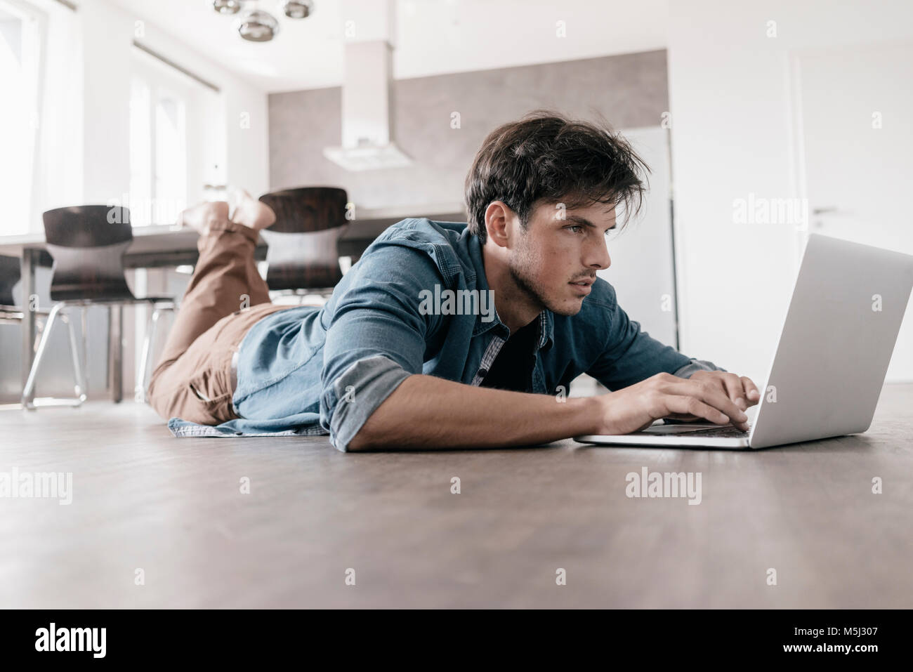 Man lying on the floor in a loft using laptop Stock Photo - Alamy