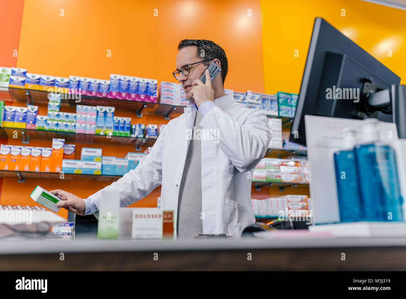 Pharmacist talking on phone at counter in pharmacy Stock Photo - Alamy