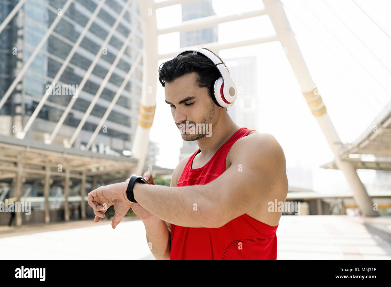 Athlete with earphones checking his smartwatch Stock Photo - Alamy