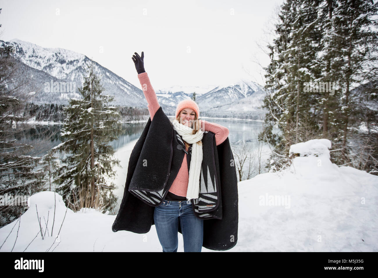 Portrait of happy young woman in alpine winter landscape with lake ...