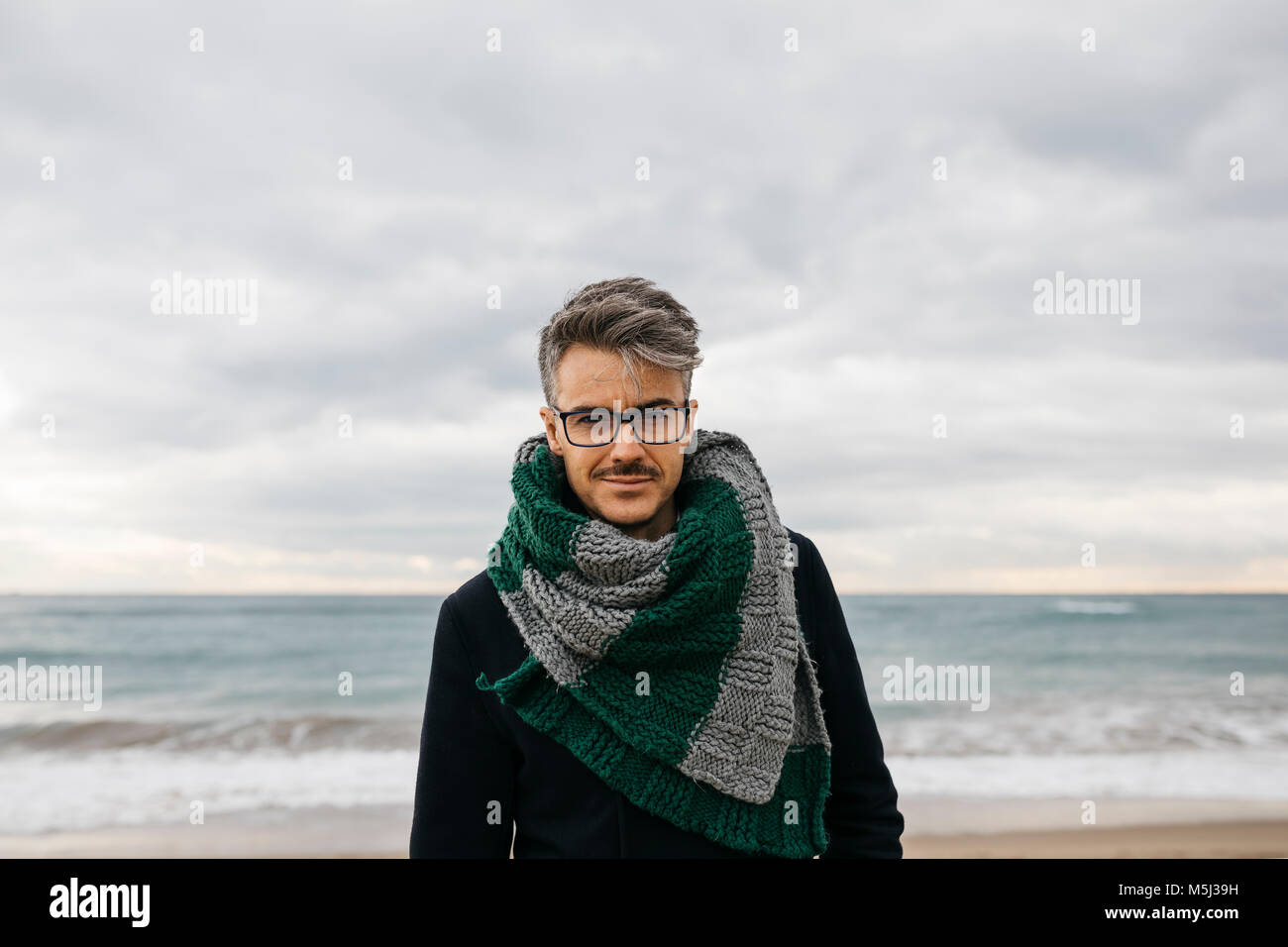 Portrait of man on the beach wearing knitted scarf Stock Photo - Alamy