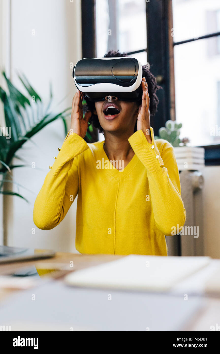 Laughing young woman playing game, wearing virtual reality goggles ...