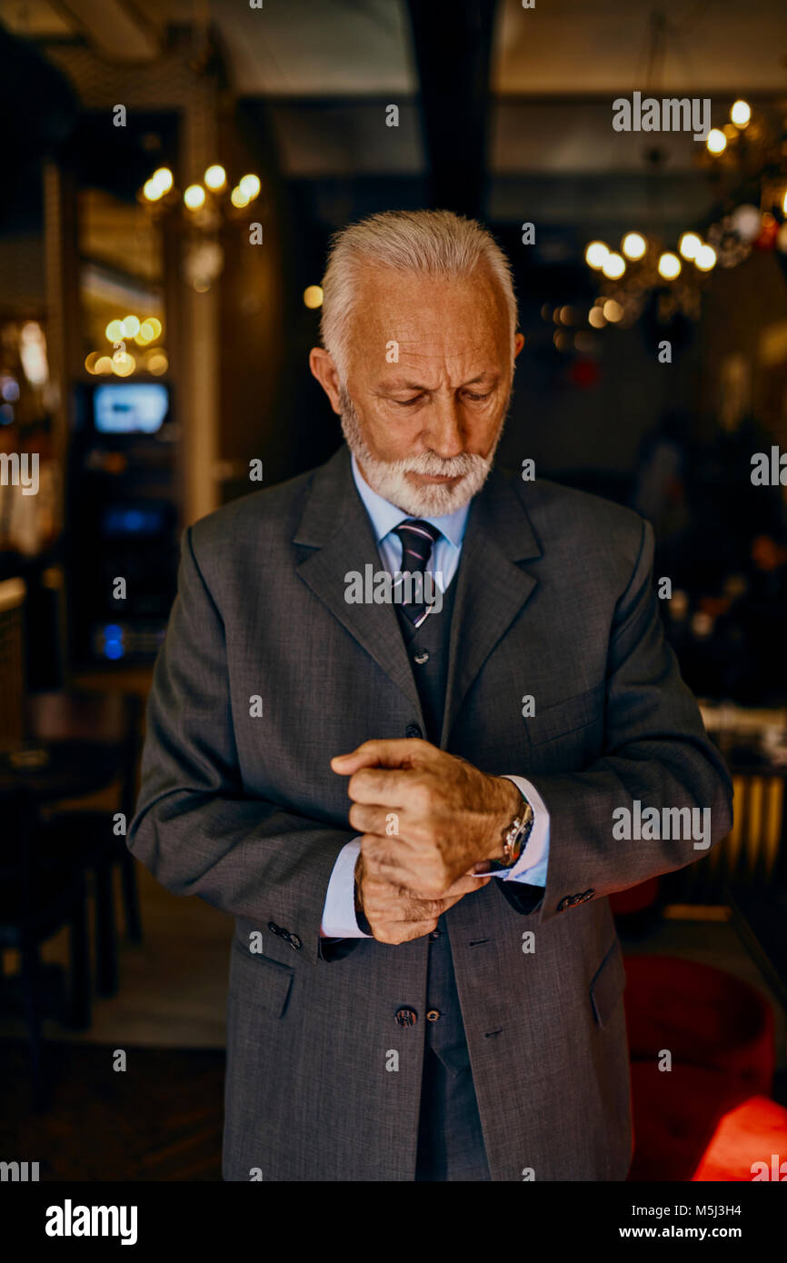 Elegant senior man adjusting his cuffs Stock Photo - Alamy