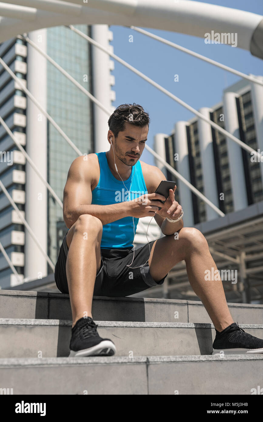 Runner wearing earphones, checking messages on his smartphone Stock ...