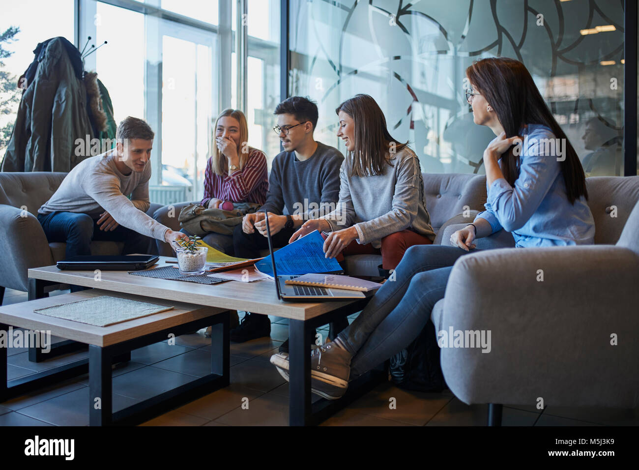 Group of friends sitting together in a cafe with laptop and documents ...