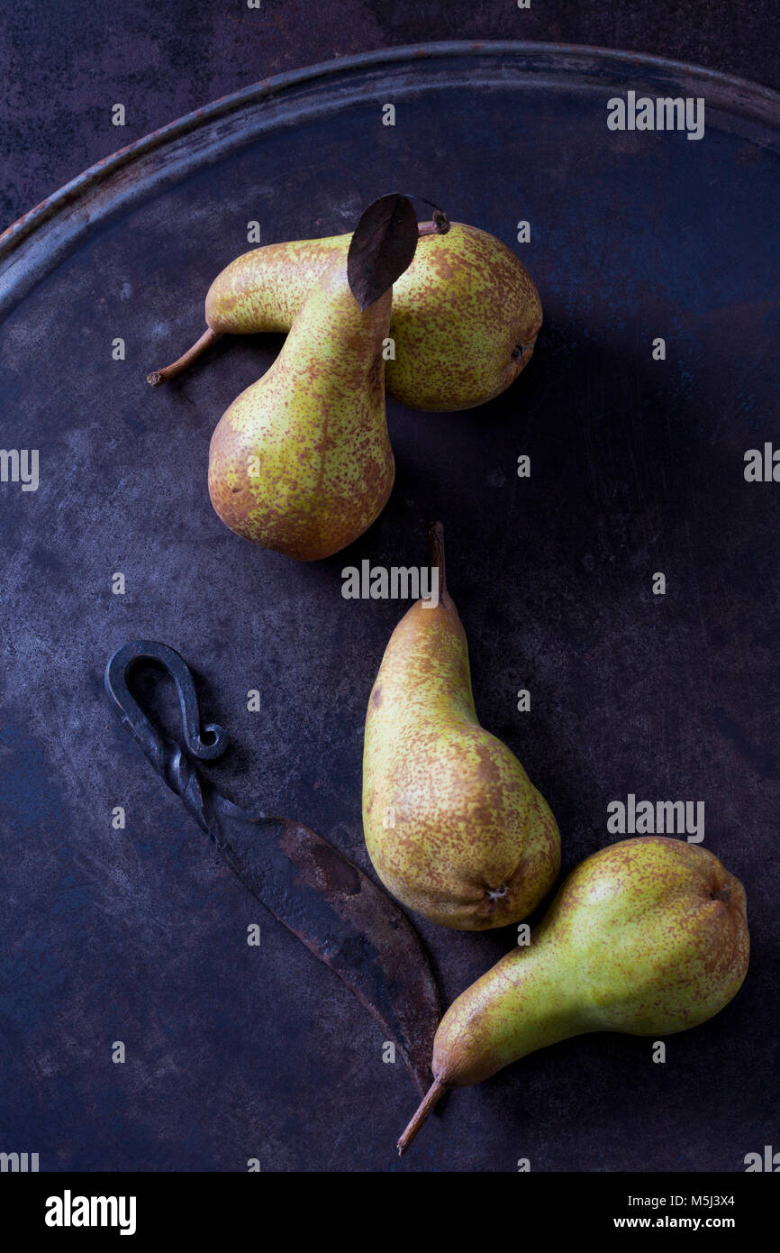 Four green pears 'Abate Fetel' and an old knife on rusty ground Stock ...