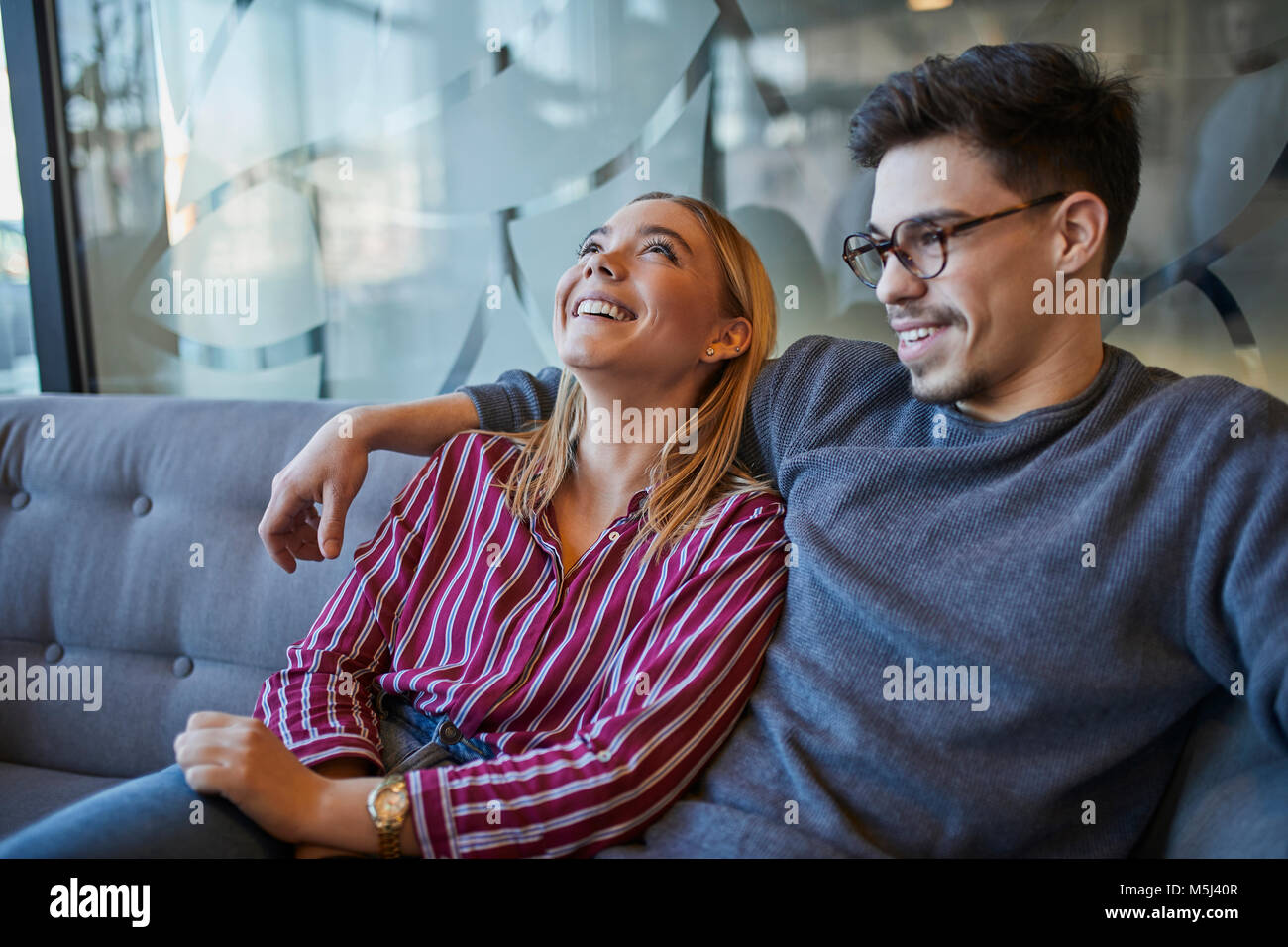 Happy relaxed couple sitting on sofa in a cafe Stock Photo - Alamy