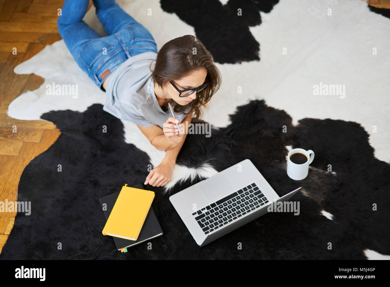 Young woman at home lying on the floor using laptop Stock Photo - Alamy