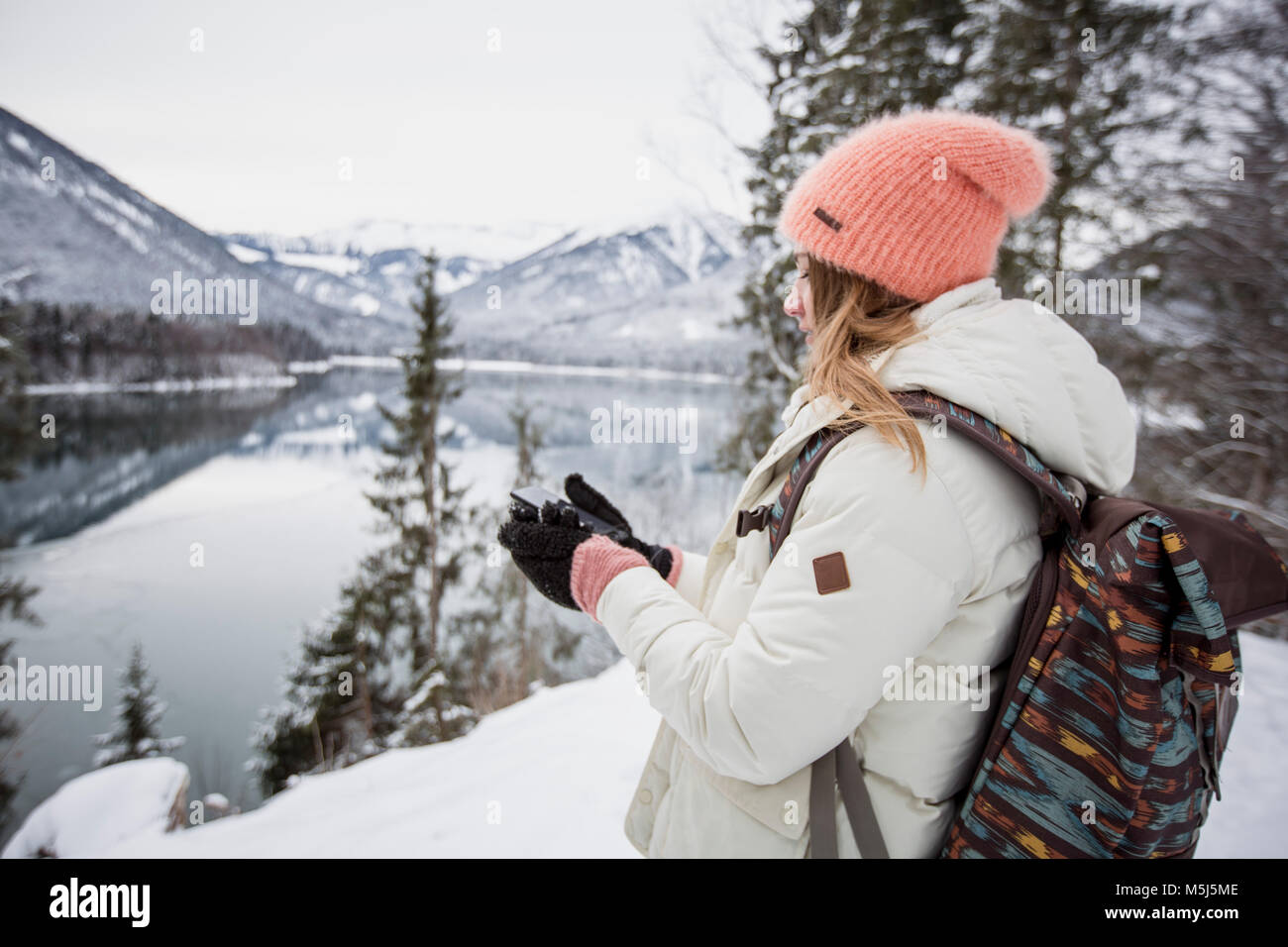 Young woman with cell phone in alpine winter landscape with lake Stock ...