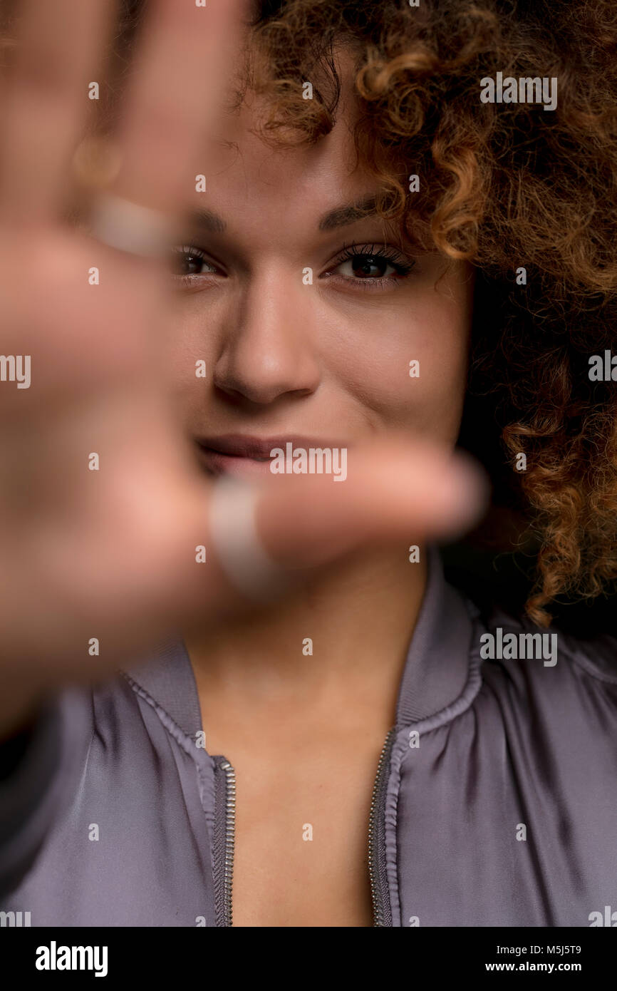 Portrait of smiling young woman raising her hand Stock Photo - Alamy