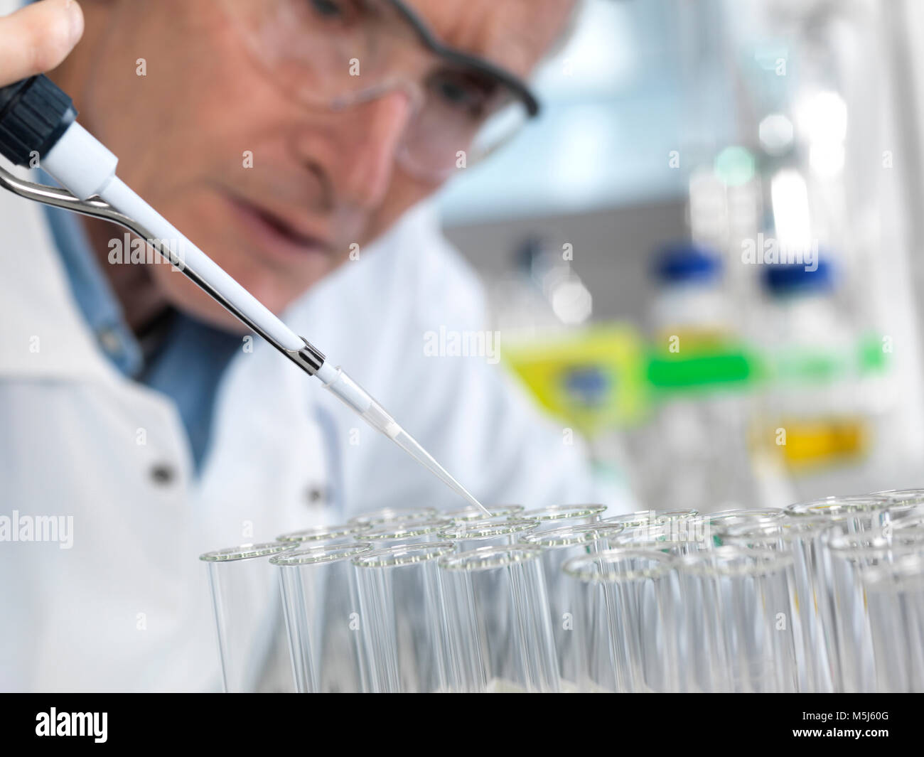 Scientist pipetting into test tubes during an experiment in the ...