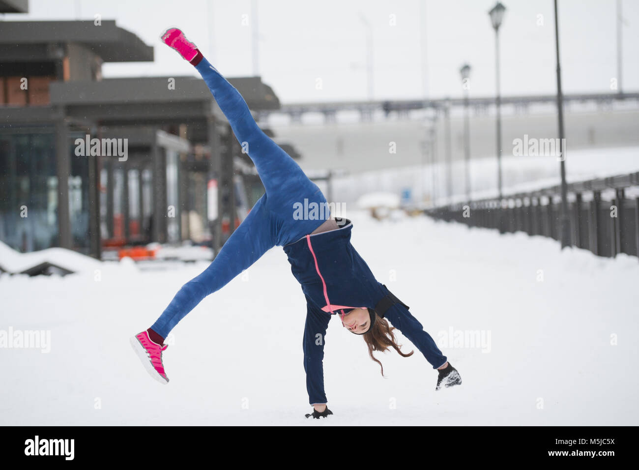 Fitness girl have acrobatic work out fitness on snow winter outdoor ...