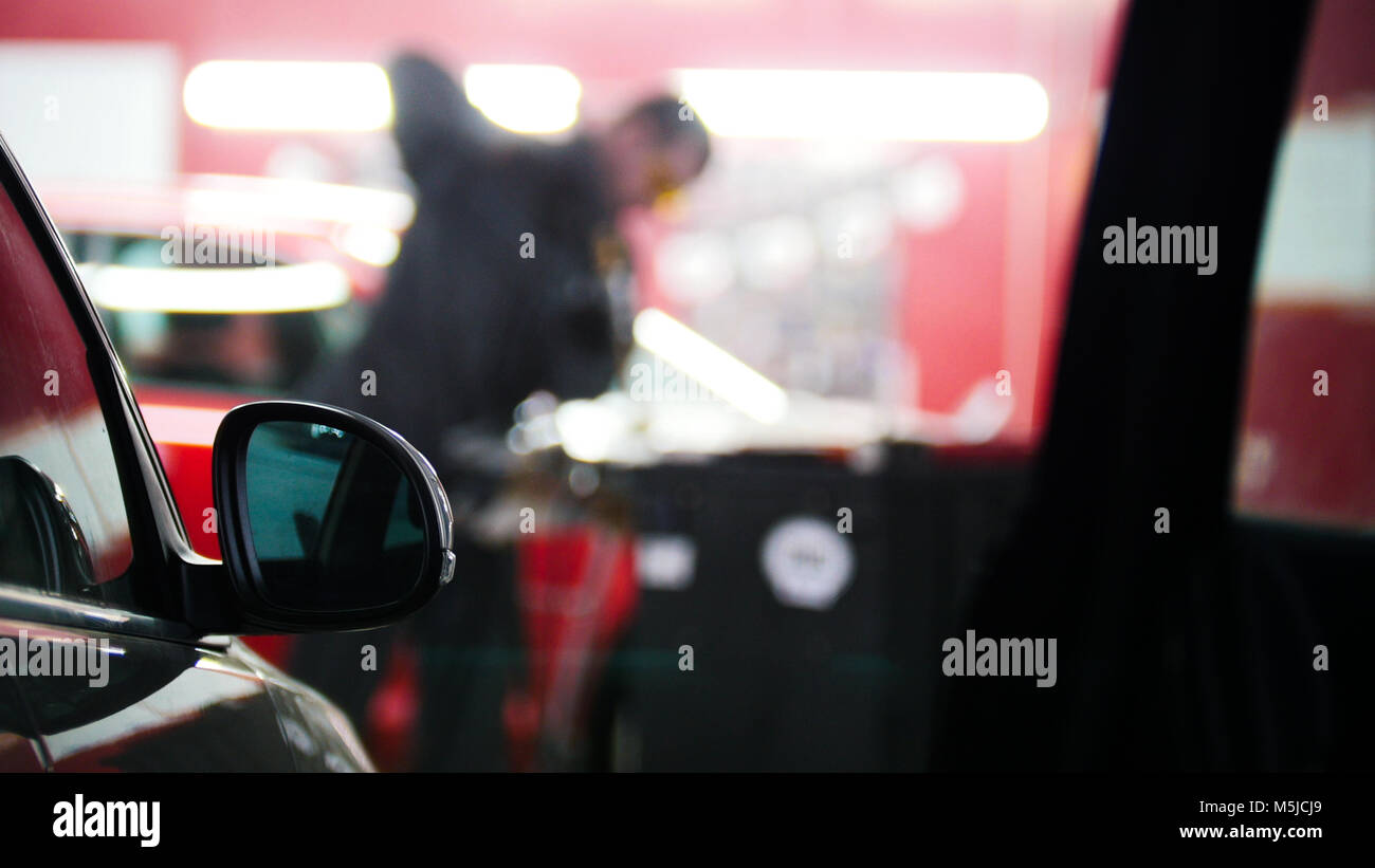 Defocused background - car service - man worker repairing automobile ...
