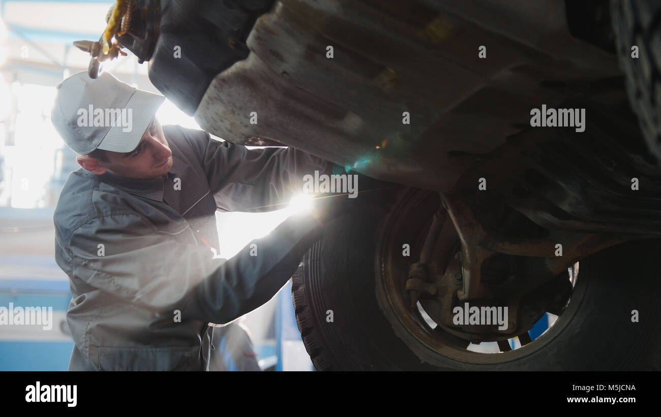 Garage automobile service - a mechanic working the wheel, backlight ...