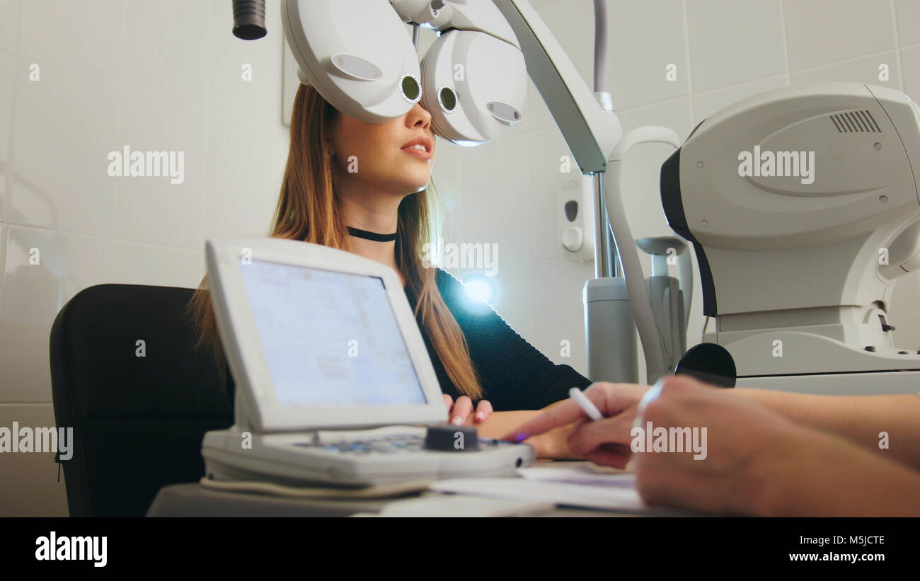 Blonde young female doing eye test with optometrist in medical center ...