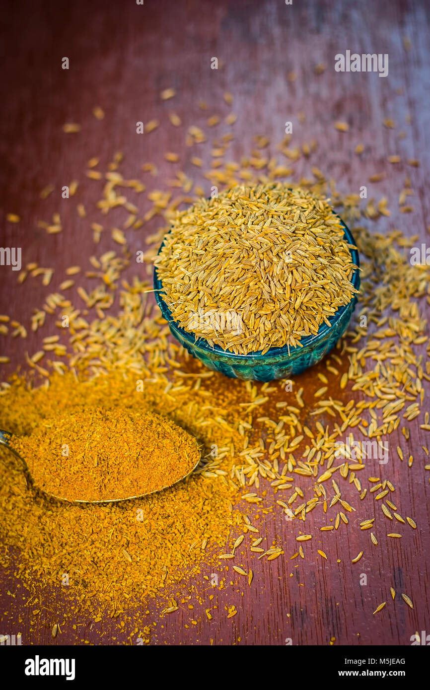 Close up of cumin,Cuminum cyminum and its powder in a spoon on a wooden ...