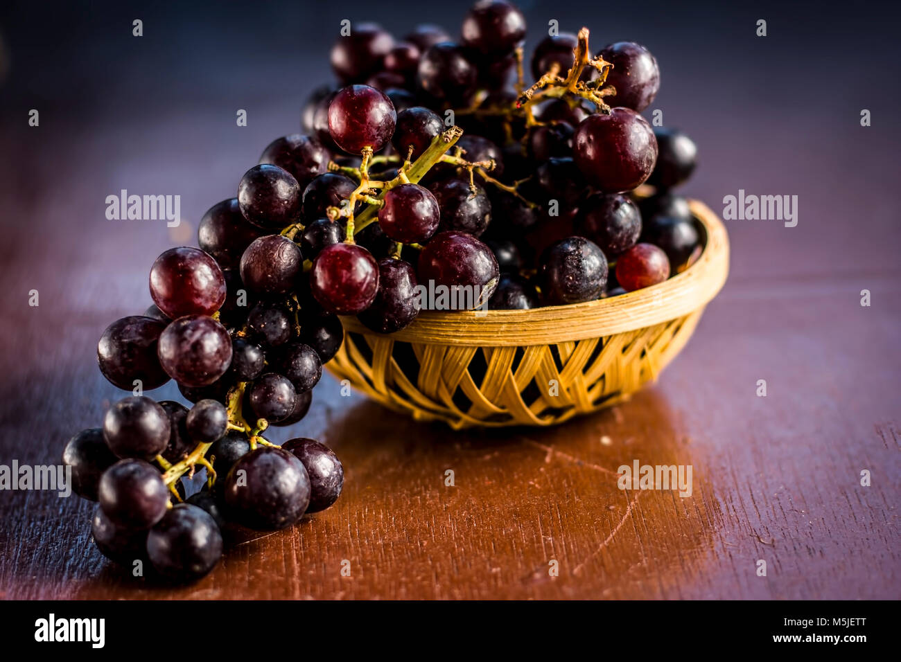 Close up of Grapes,Vitis vinifera in a basket on a brown wooden surface ...