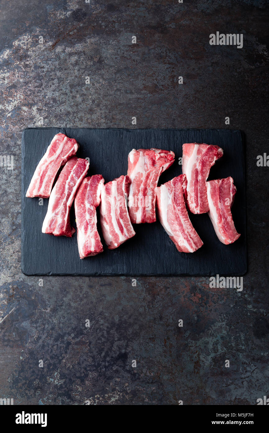 Raw uncooked pork ribs, fresh meat on dark metal background. Top view ...