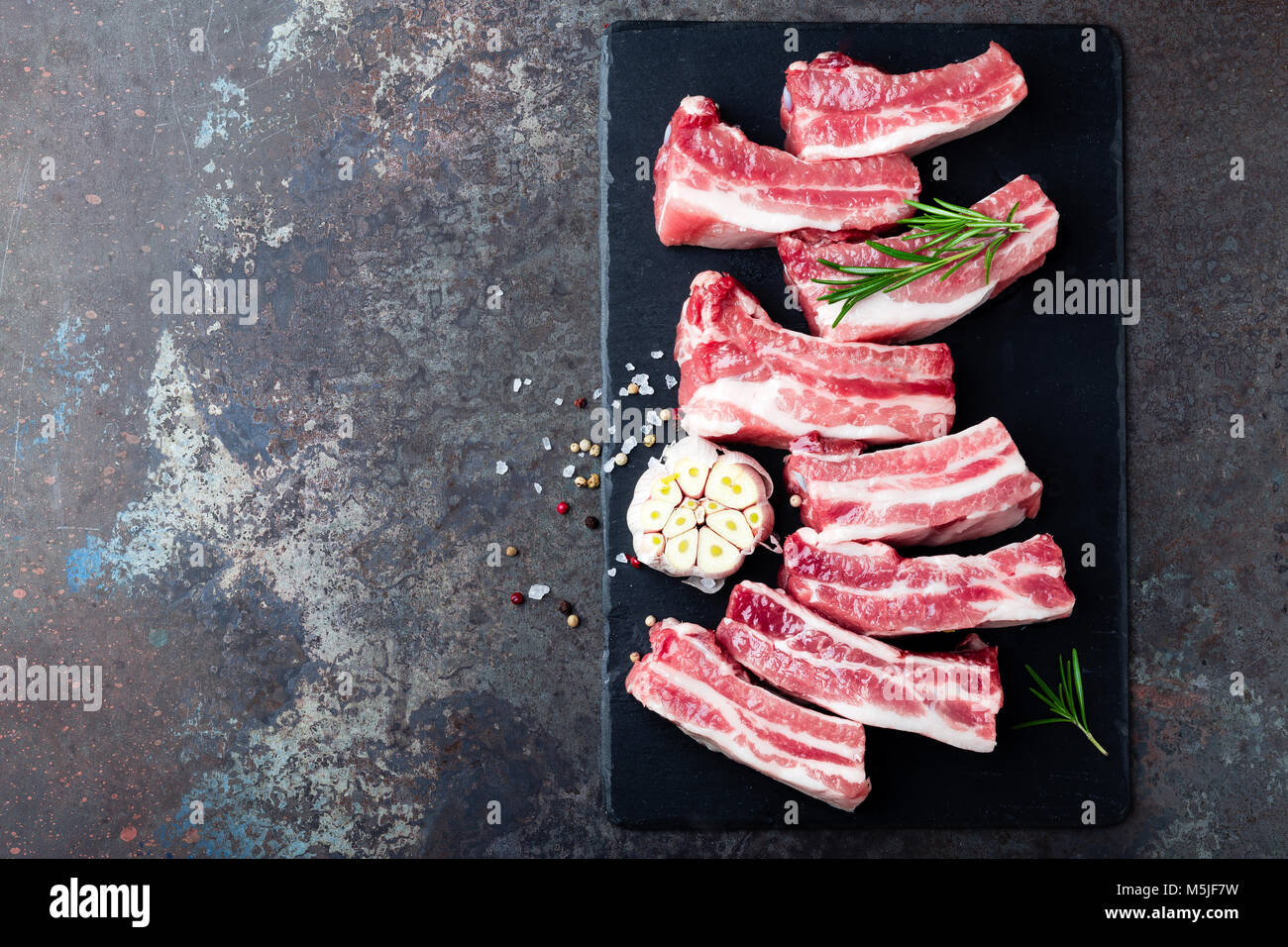 Raw uncooked pork ribs, fresh meat on dark metal background. Top view ...