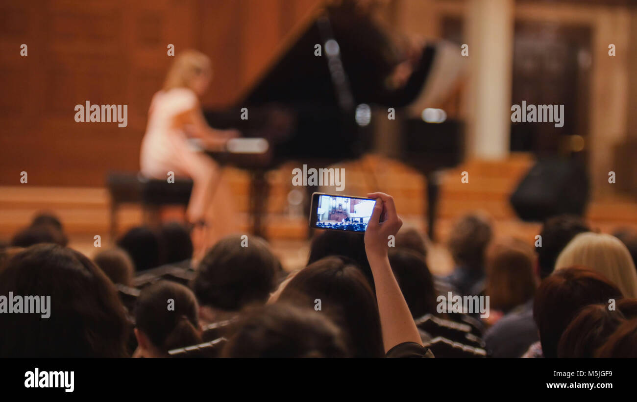 Audience in concert hall during performing piano girl- people shooting ...