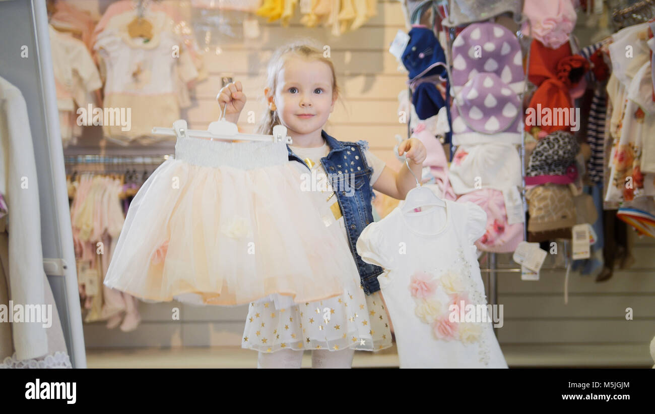 Shopping for girls - blonde little girl showing new purchases in store ...