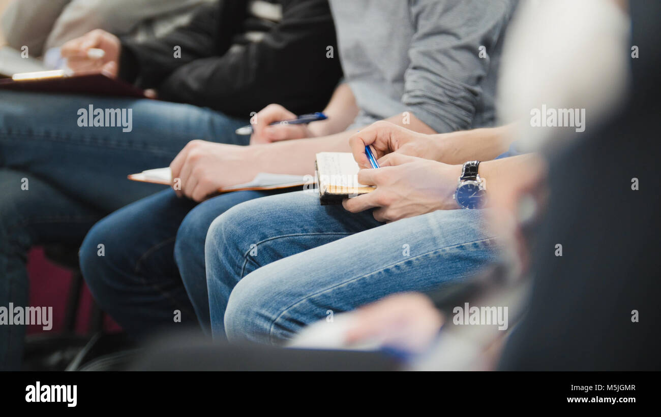 People at presentation n business hall at lecture and taking notes ...