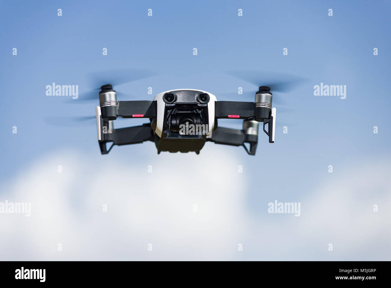 A DJI Mavic Air drone in flight against a blue sky with clouds Stock ...