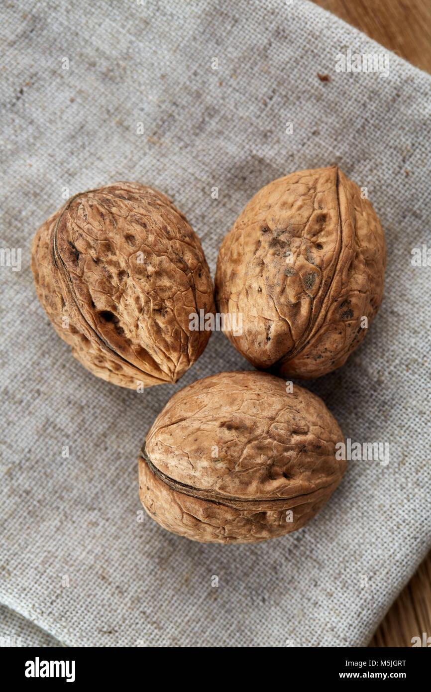 A stack of hard shells of walnuts piled together on light grey fabric ...