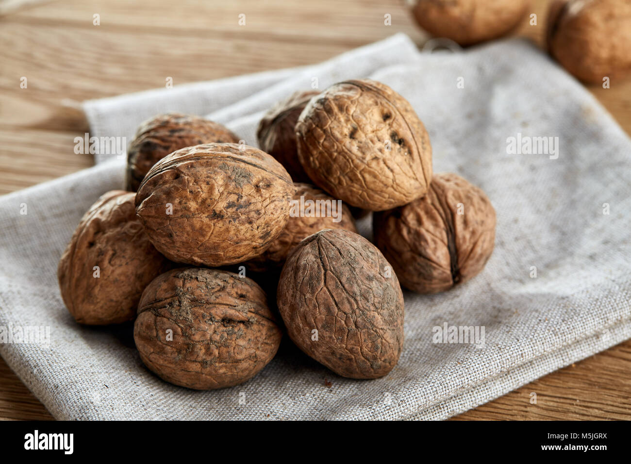 A stack of hard shells of walnuts piled together on light grey fabric ...