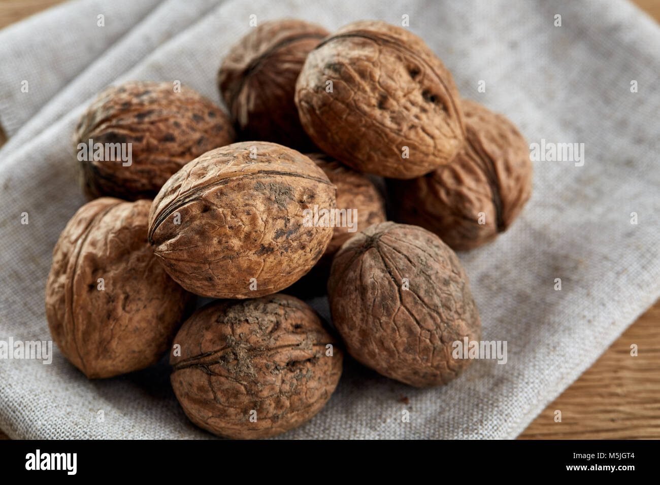 A stack of hard shells of walnuts piled together on light grey fabric ...