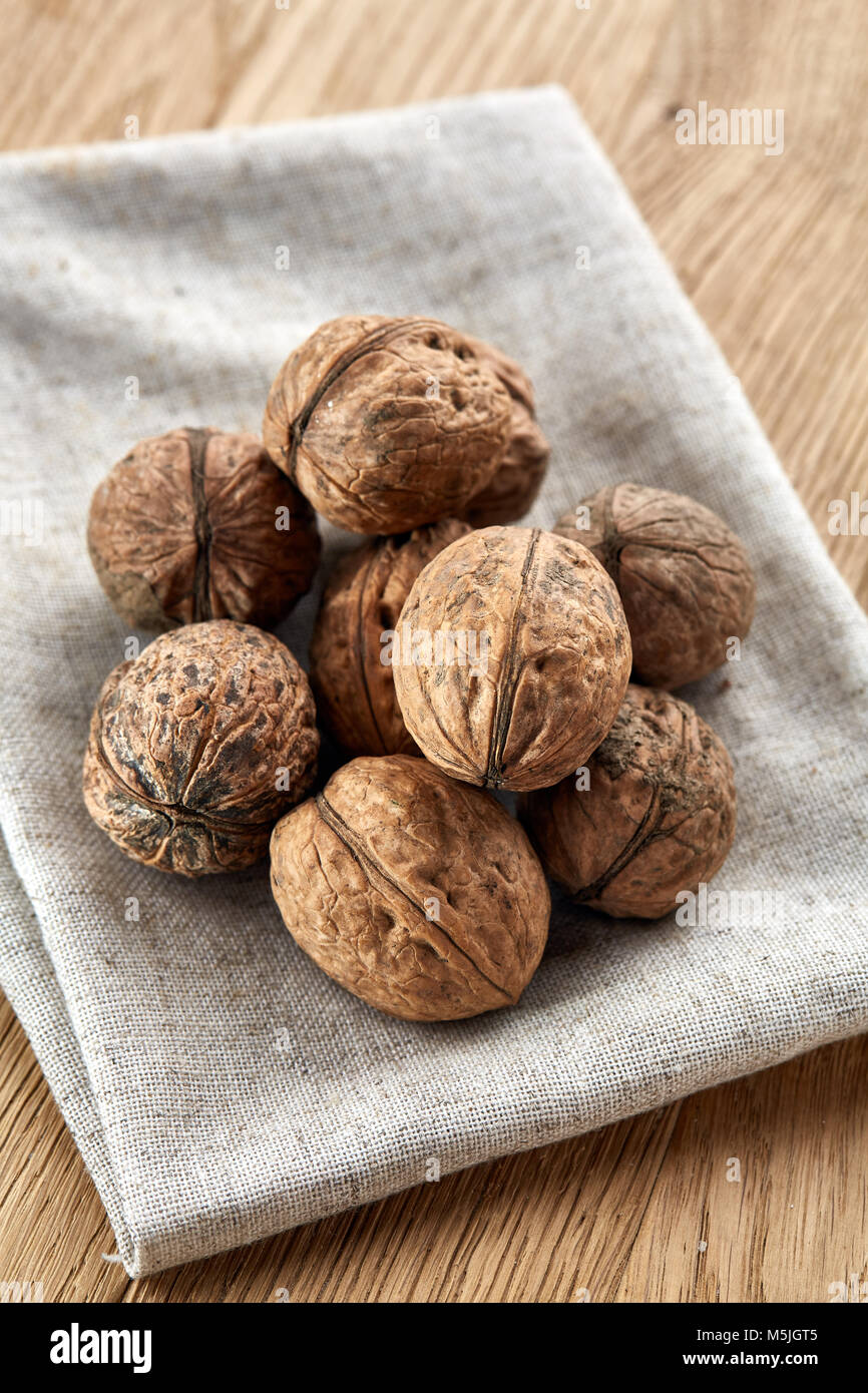 A stack of hard shells of walnuts piled together on light grey fabric ...