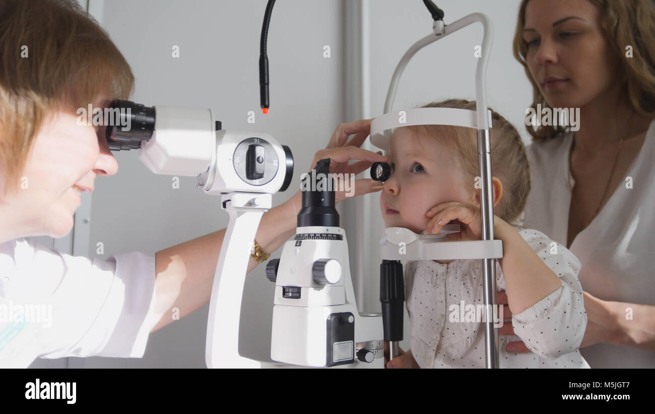 Optometrist checks little girl's eyesight - mother and child in ...