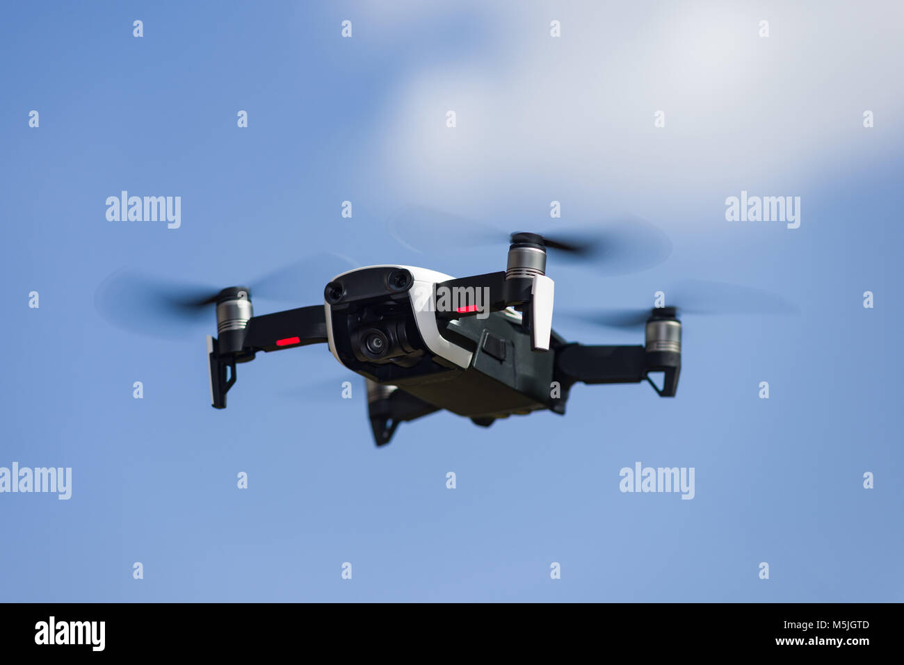 A DJI Mavic Air drone in flight against a blue sky with clouds Stock ...