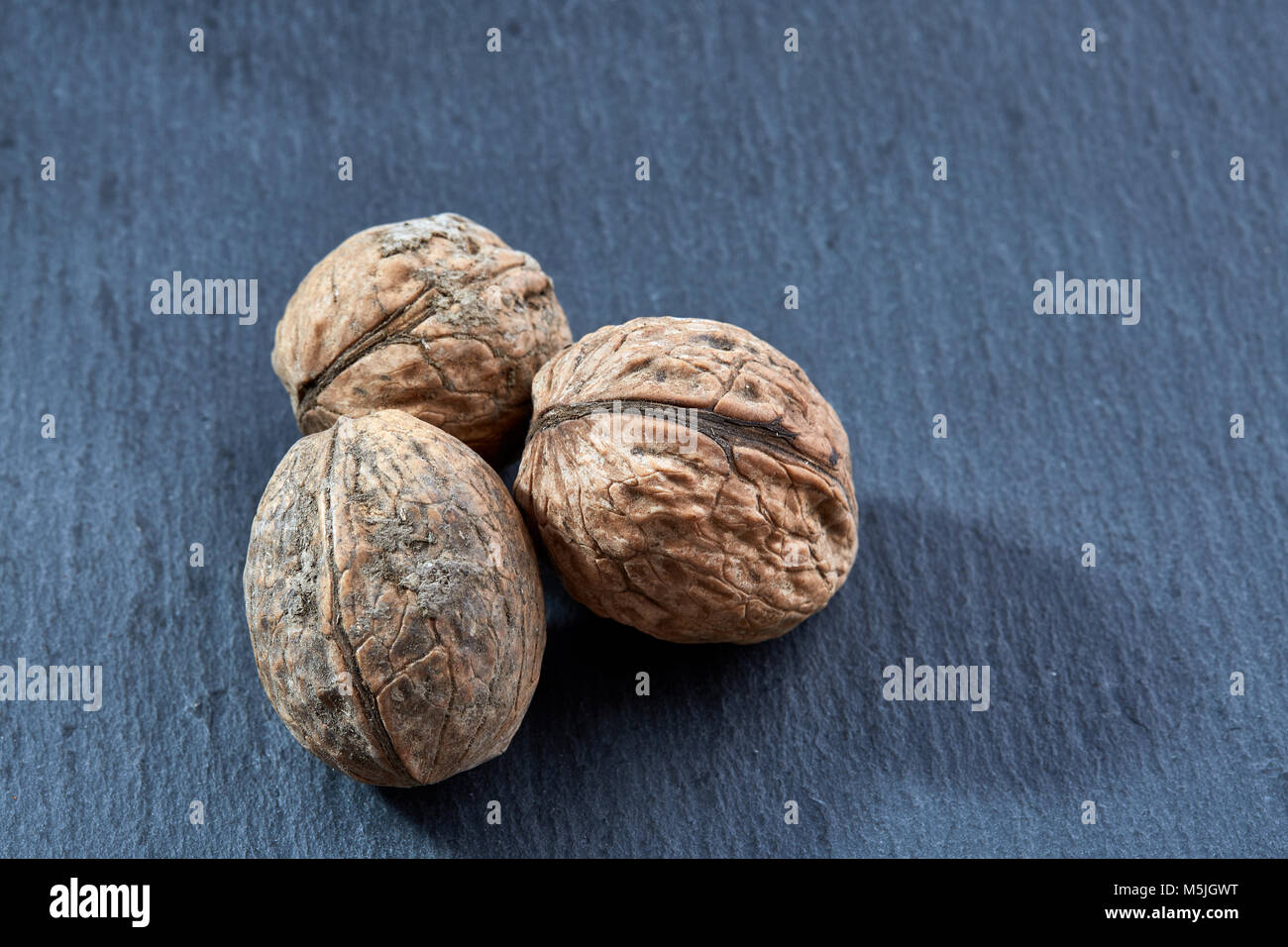 A stack of hard shells of walnuts piled together on dark stony ...
