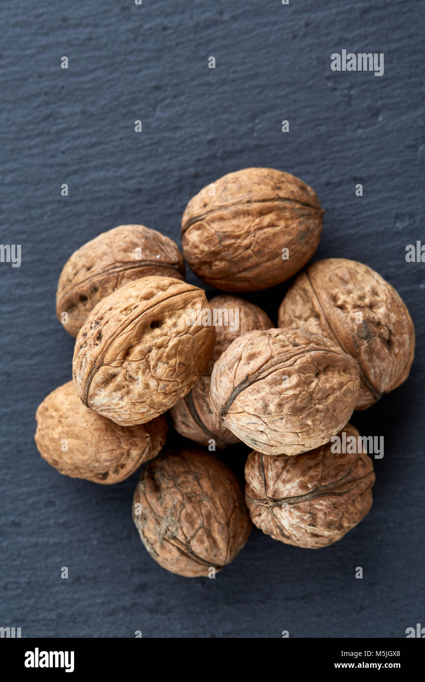A stack of hard shells of walnuts piled together on dark stony ...