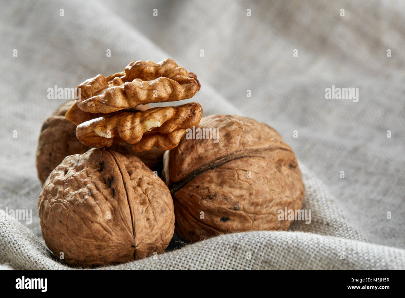 A stack of hard shells of walnuts piled together on light grey fabric ...