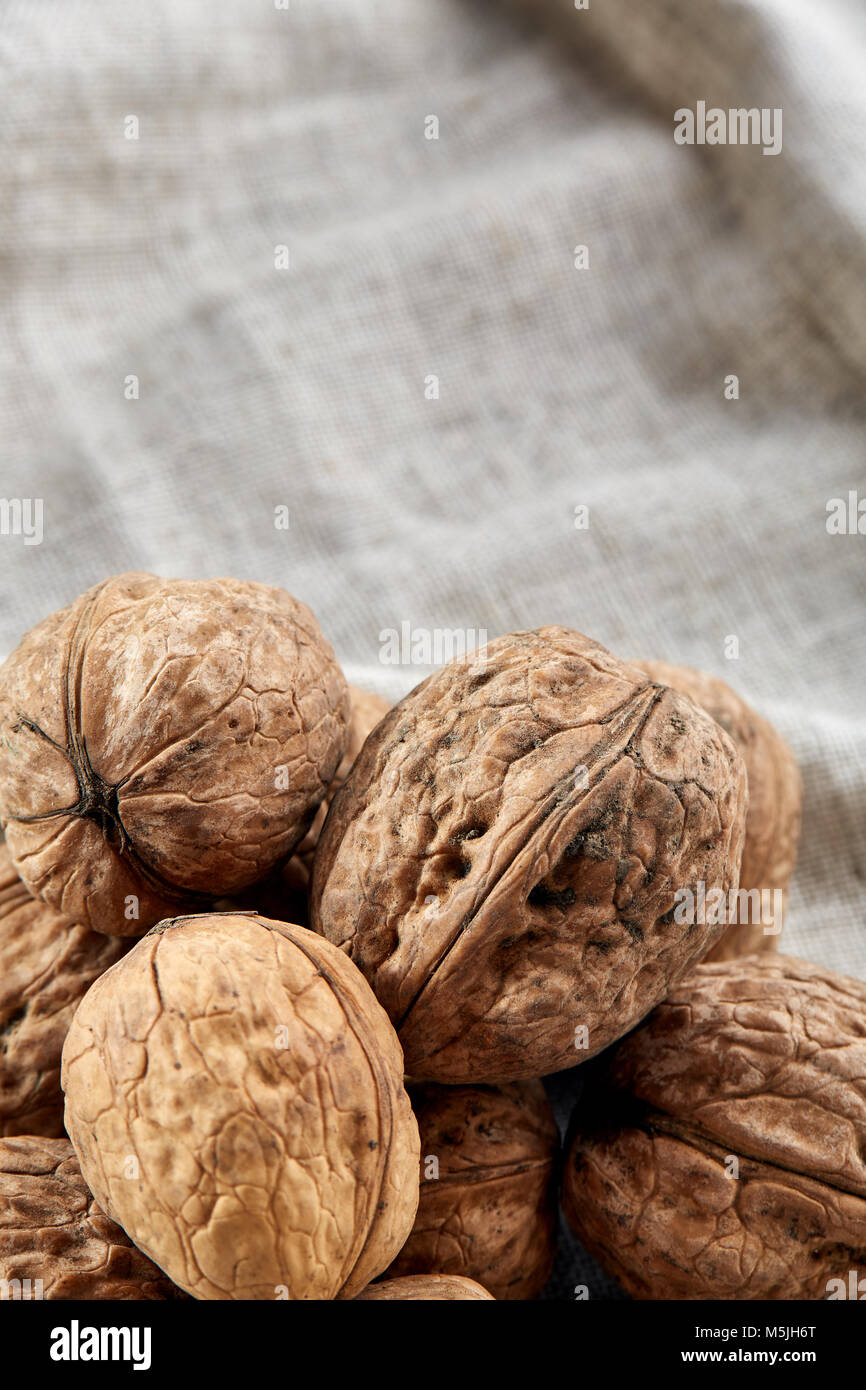 A stack of hard shells of walnuts piled together on light grey fabric ...