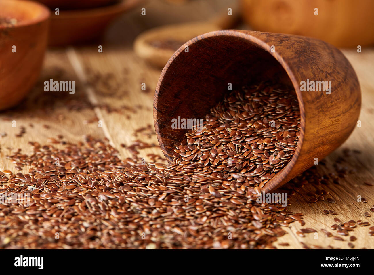 An overturned wooden bowl with linseeds on a brown rustic wooden ...