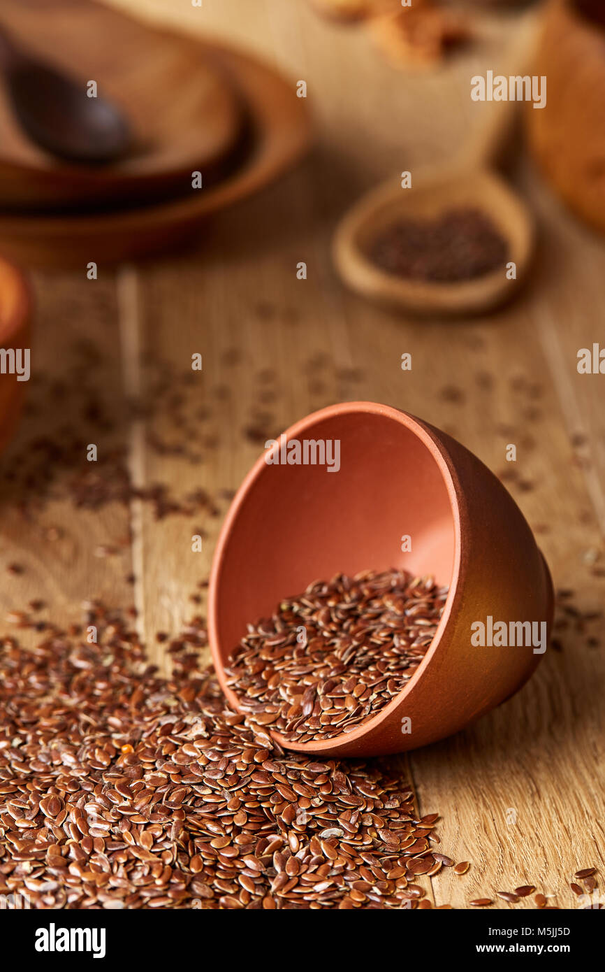 An overturned ceramic clay bowl with linseeds on a brown rustic wooden ...