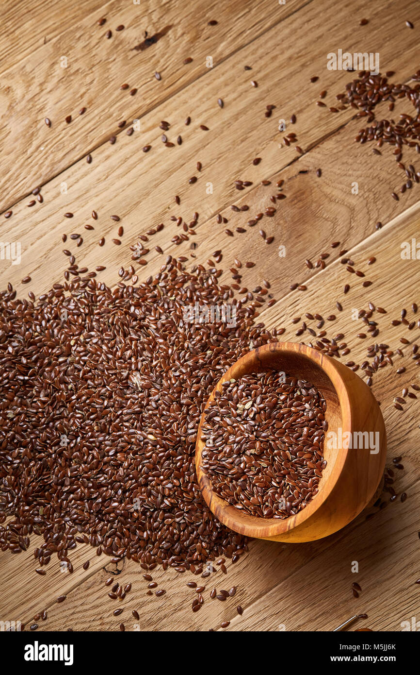 An overturned wooden bowl with linseeds on a brown rustic wooden background seen from the ...