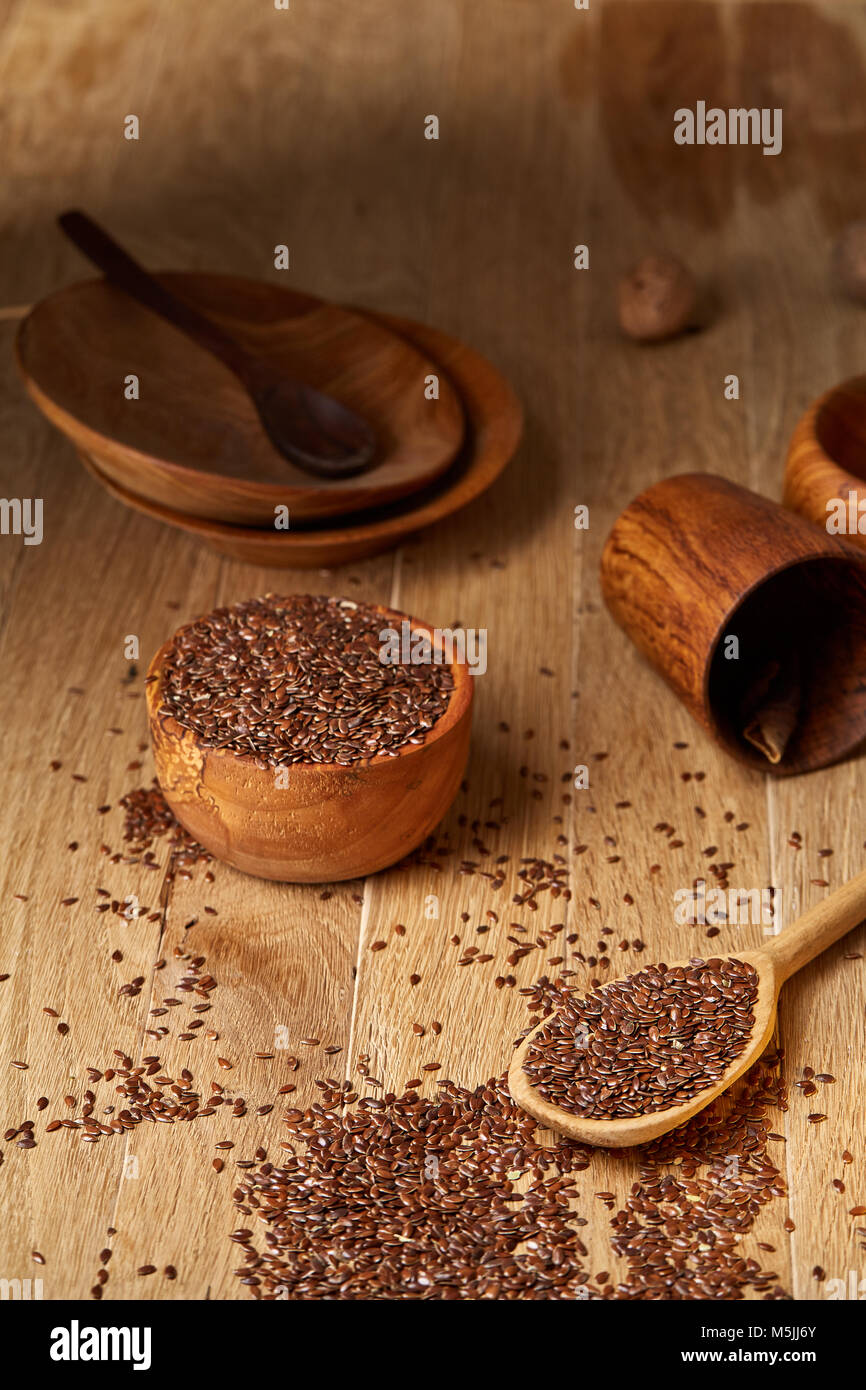Top view, close-up picture of wooden spoon full of flax seeds over some seeds composed on rustic ...