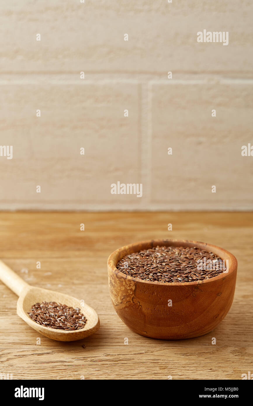 Top view, close-up picture of wooden spoon full of flax seeds over some seeds composed on rustic ...