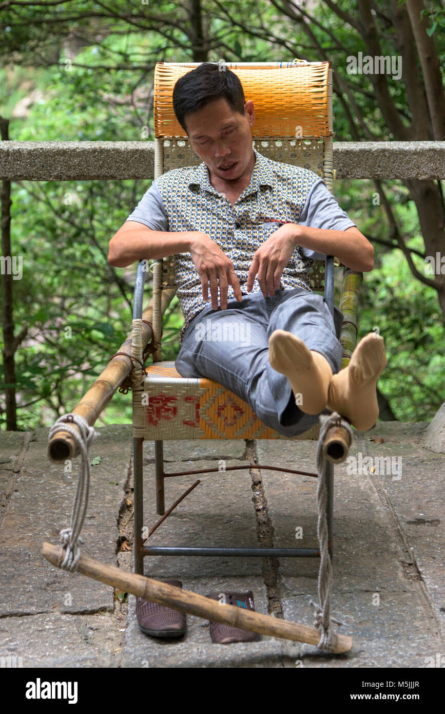 A Chinese man taking a nap from carrying people on the mountain at ...