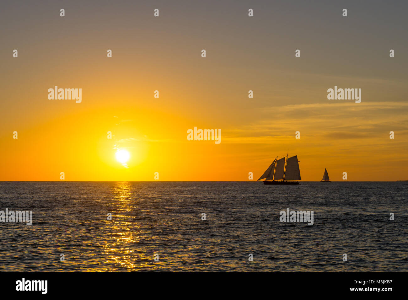 USA, Florida, Intense orange sunset sky over two silent sailing ships ...