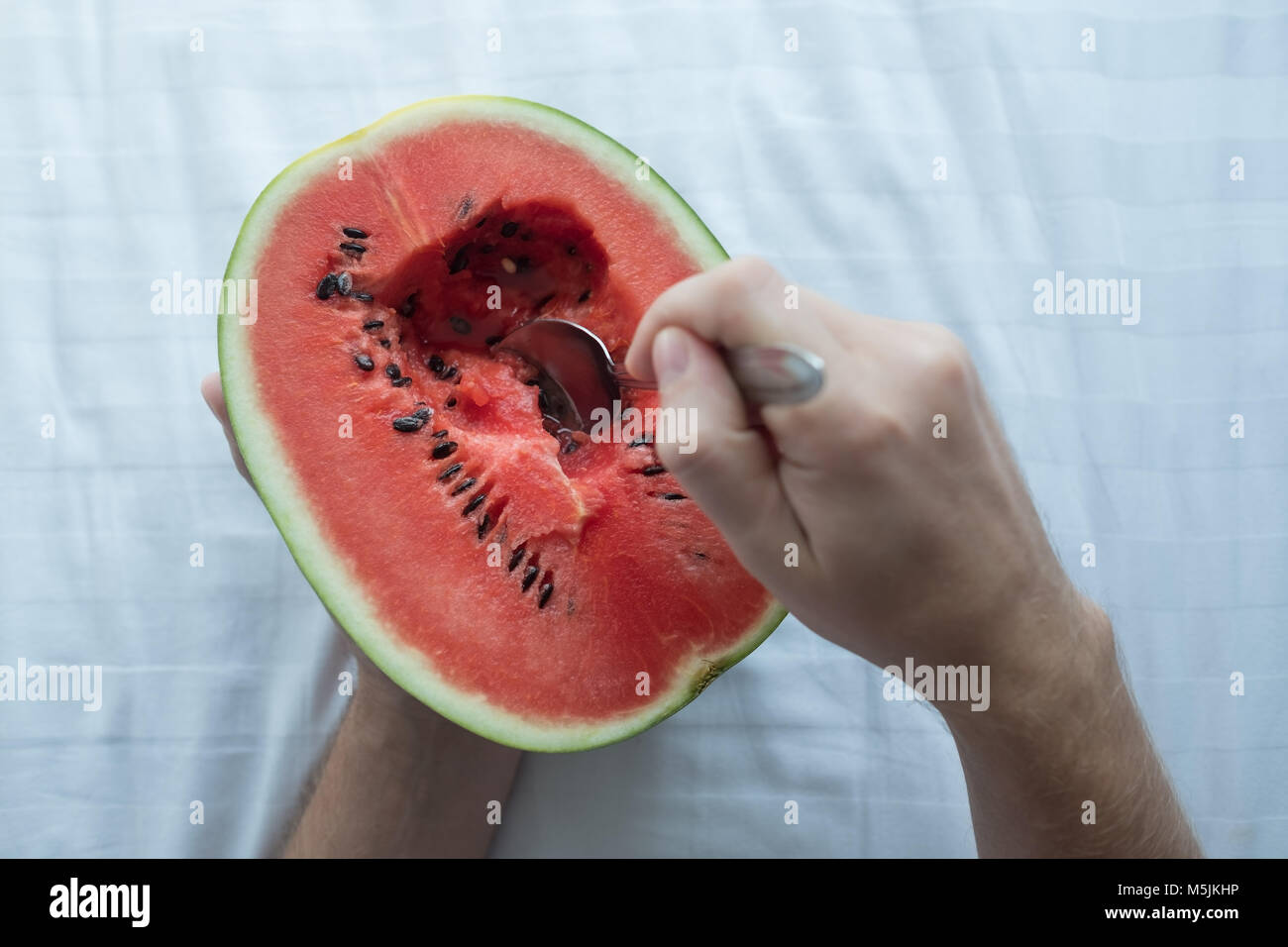 Young man eating a watermelon at home with spoon Stock Photo - Alamy