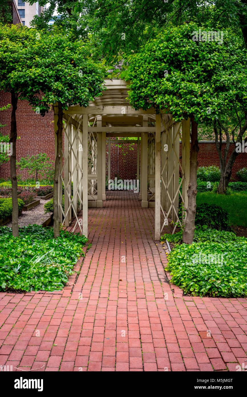 Brick path leads through a covered walkway in a fancy garden Stock ...