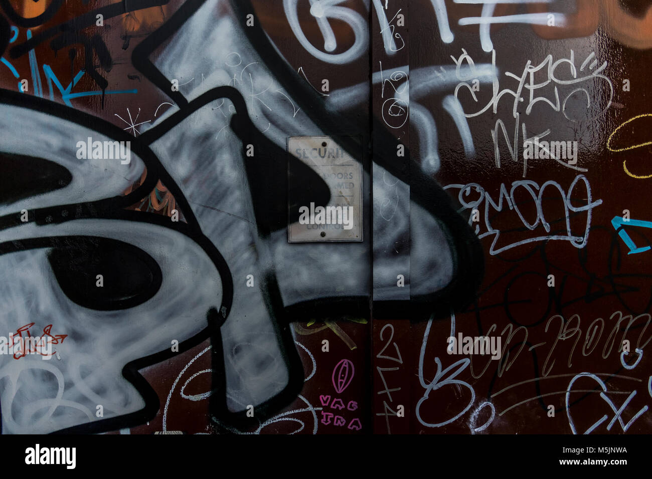 Graffiti over security sign, Bristol Stock Photo - Alamy